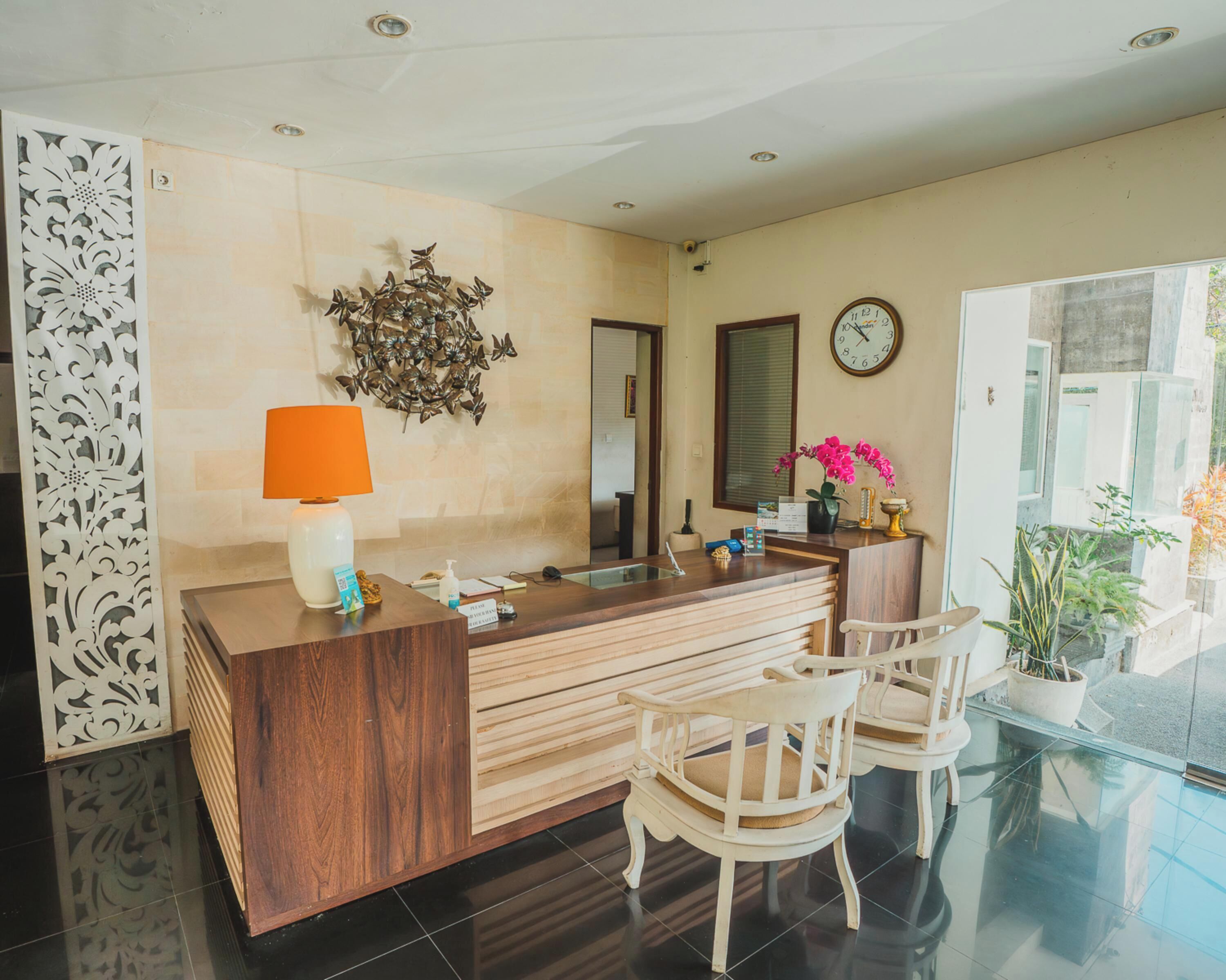 Uma casa de banho moderna com um lavatório de madeira, duas cadeiras brancas, um espelho, um relógio e arte decorativa nas paredes.