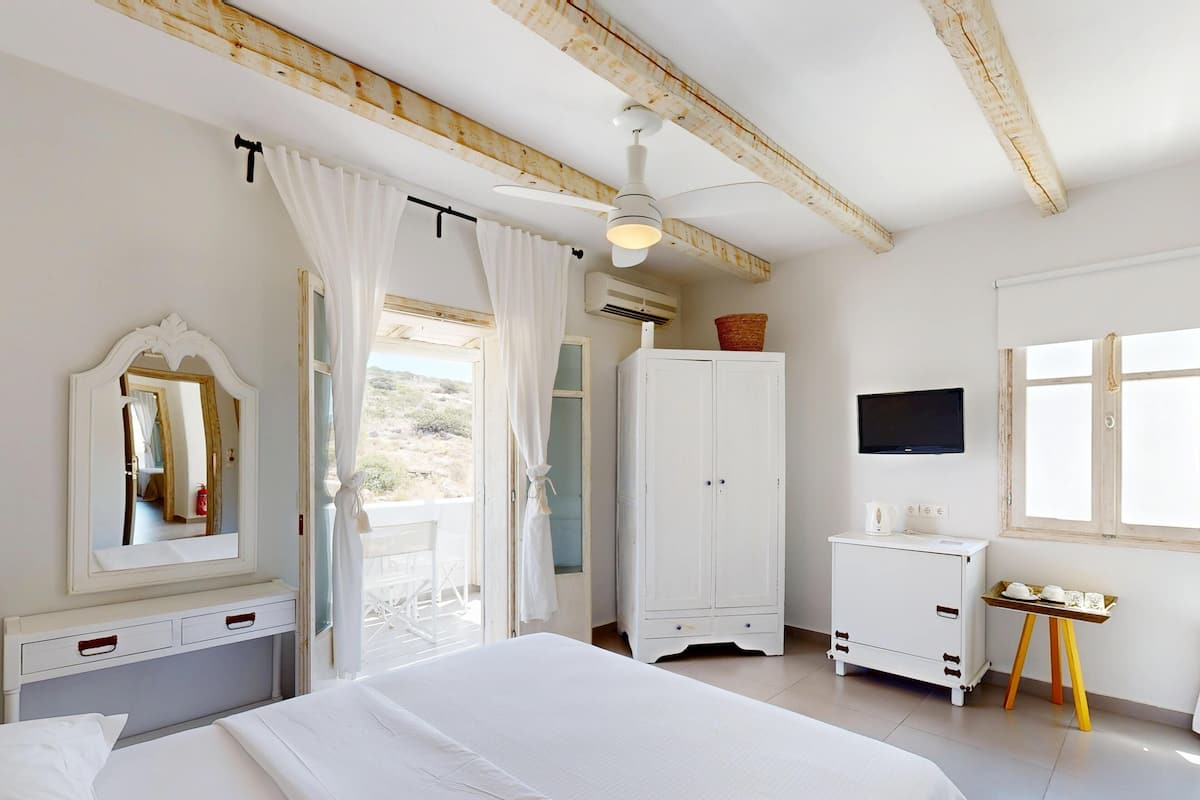Quarto com cama, guarda-roupa, televisão e janela.