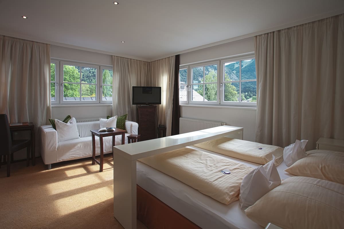 Quarto de hotel com duas camas, televisão, sofá e escrivaninha.