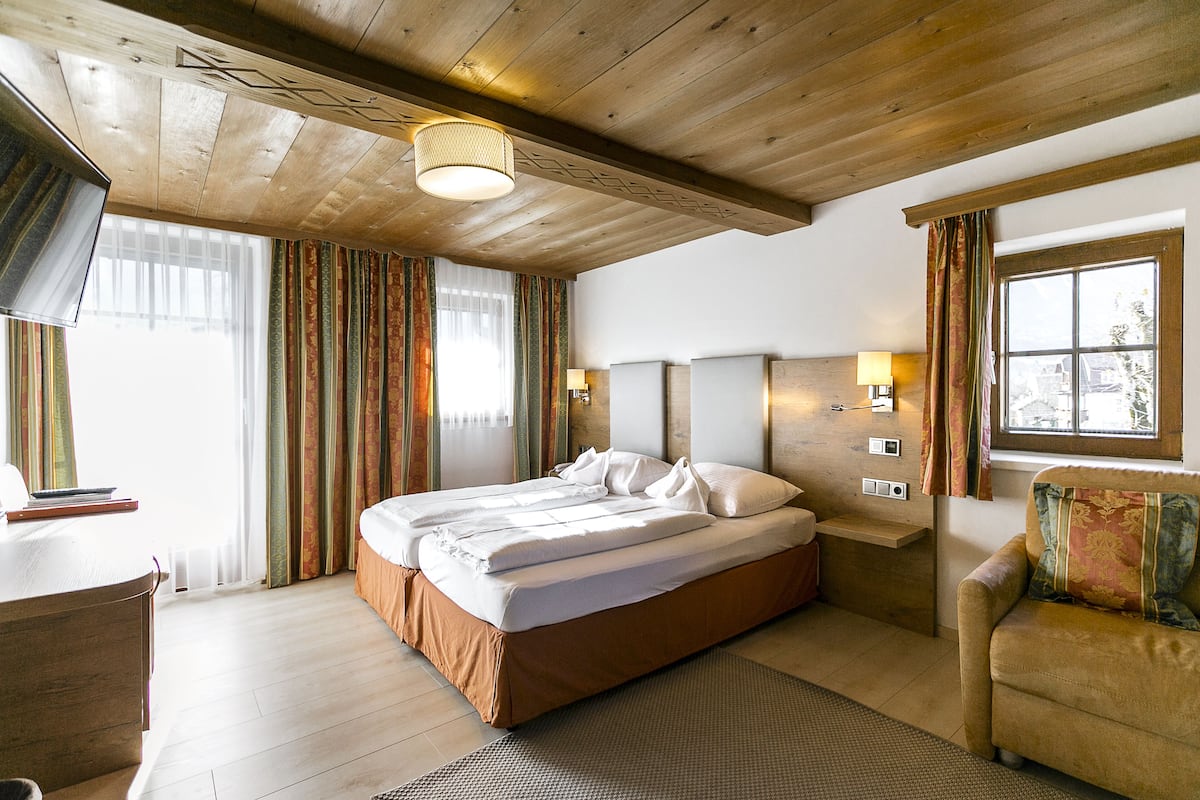 Quarto de hotel com uma cama grande, uma escrivaninha e uma cadeira.