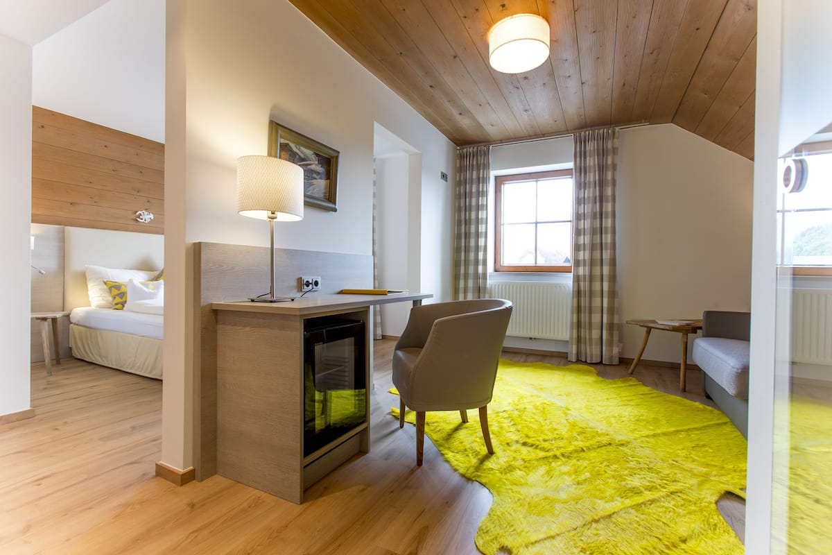 Quarto moderno com cama, mesa de cabeceira e uma pequena cozinha equipada.