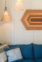 Quarto com um sofá azul, almofadas estampadas e duas luminárias pendentes.