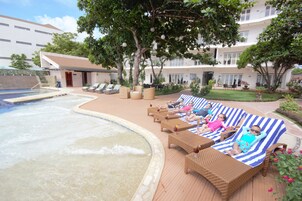 Área da piscina com espreguiçadeiras e uma banheira de hidromassagem.