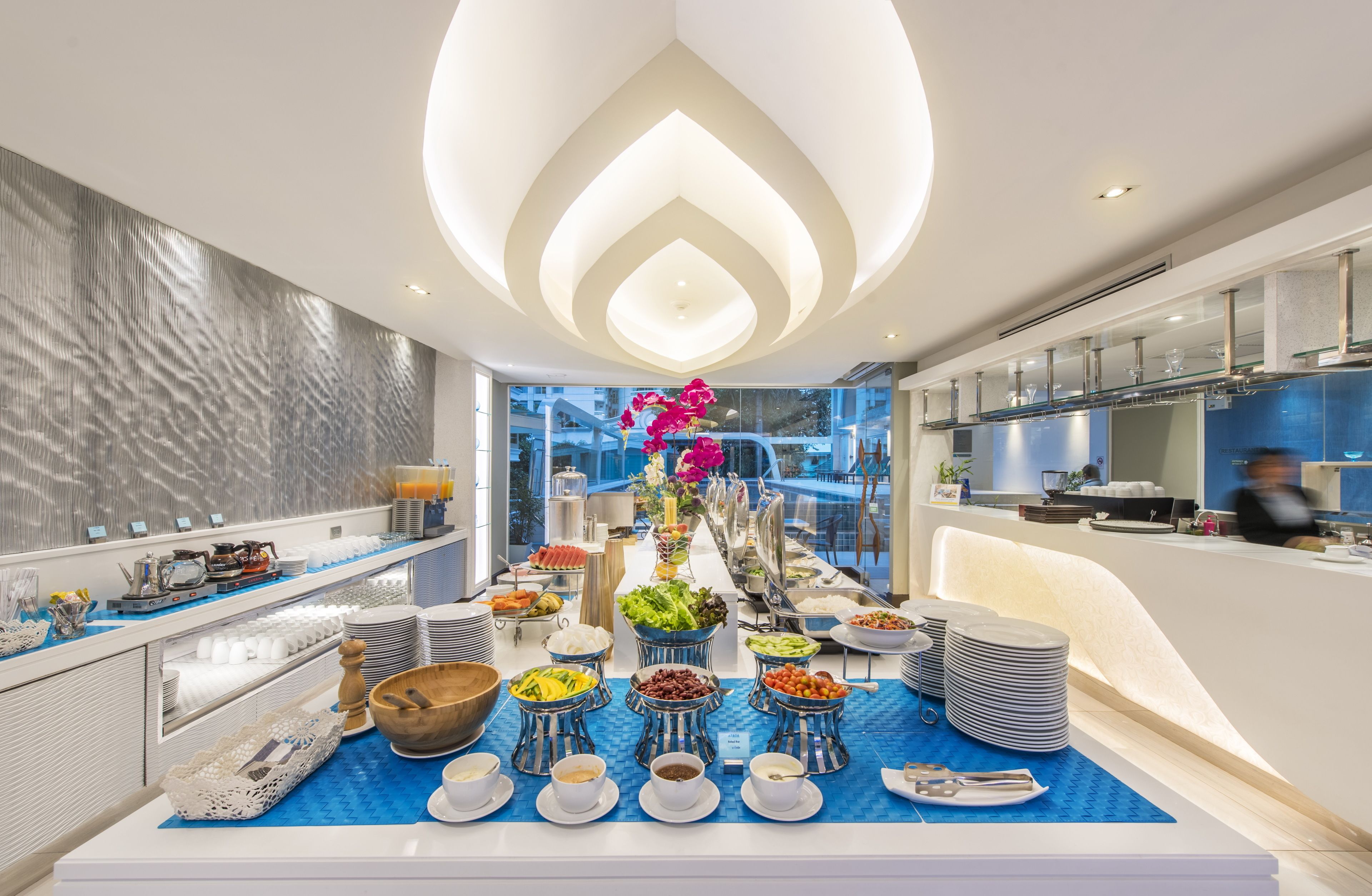 Um buffet de café da manhã moderno em hotel, com diversas opções de comida, um arranjo floral central e um design elegante e contemporâneo.