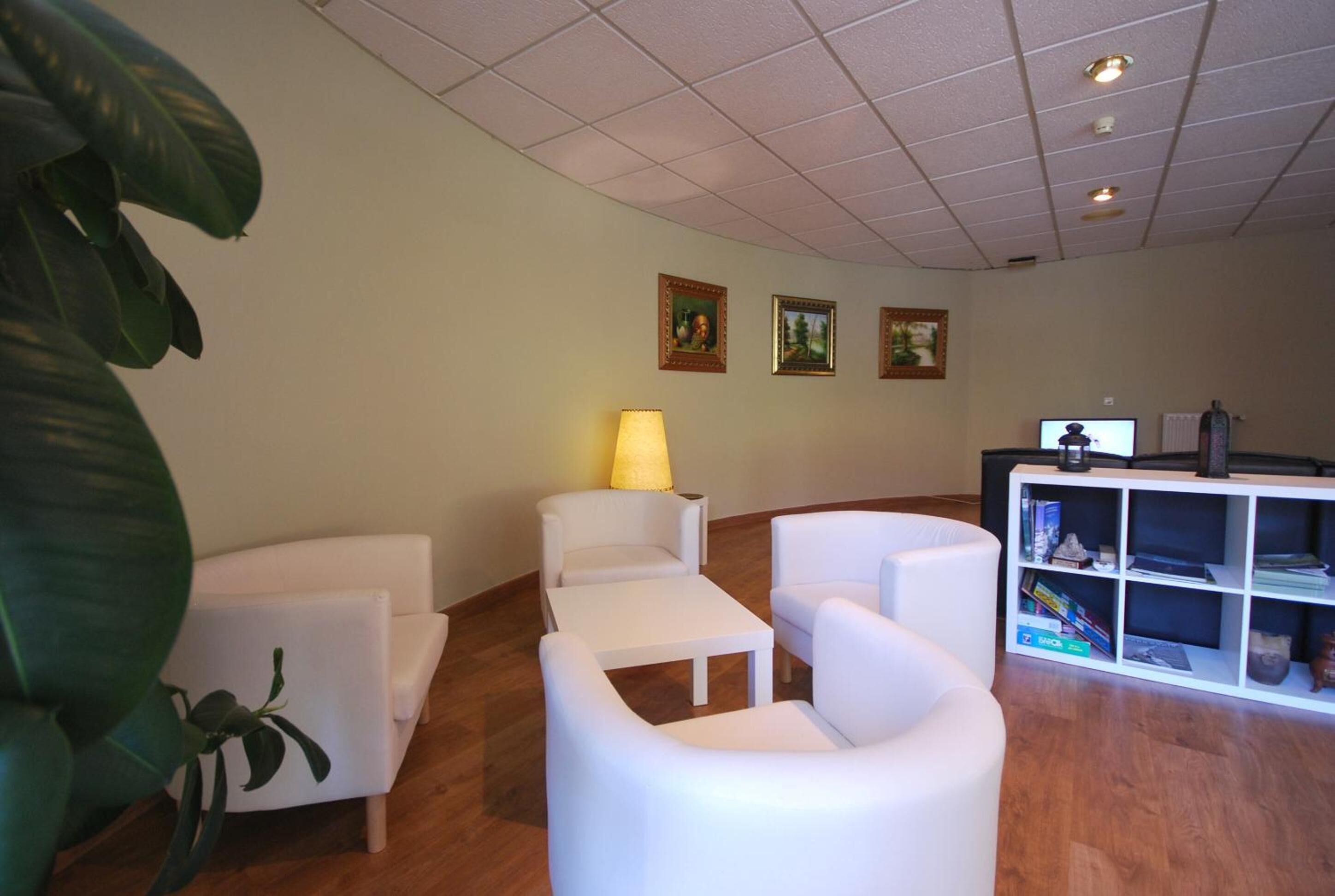 Uma sala de estar moderna com móveis brancos, uma luminária e uma estante.