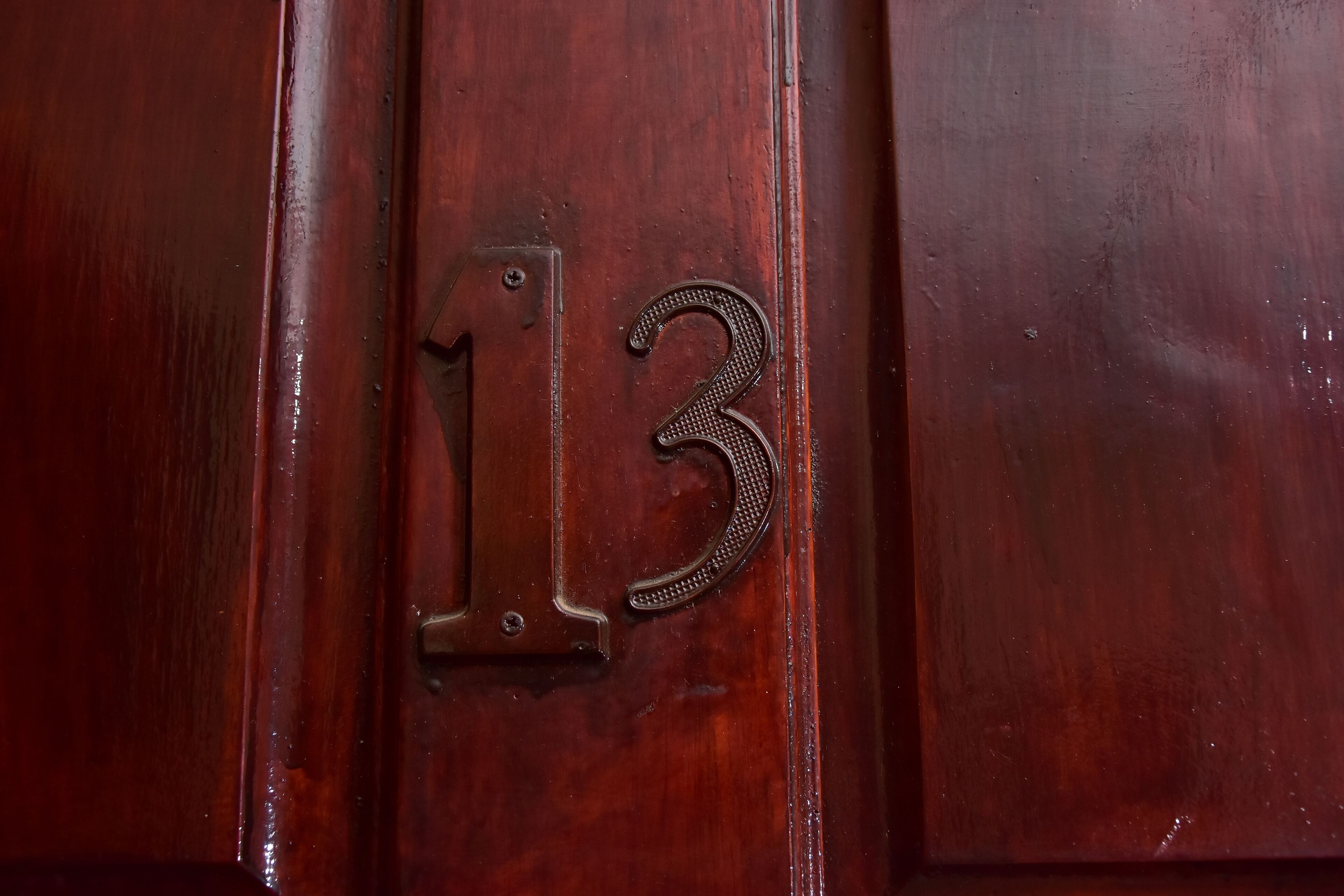 Uma porta de madeira com uma placa de metal exibindo o número 13.