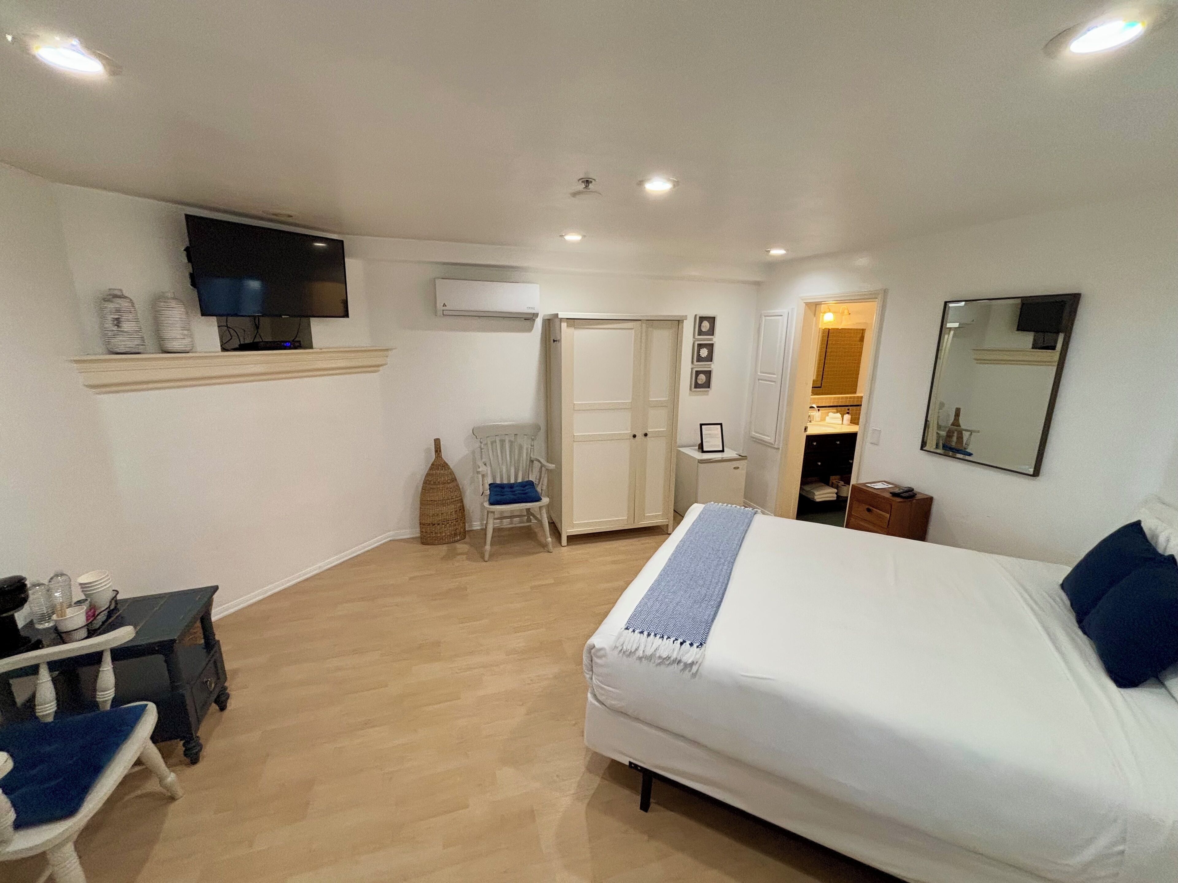 Quarto com cama, uma cadeira, escrivaninha e televisão.
