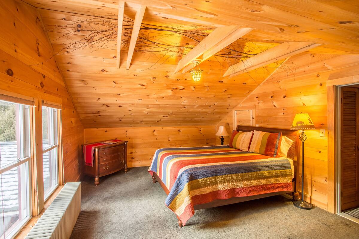 Quarto de cabana de madeira aconchegante, com cama, cômoda e janela com vista.