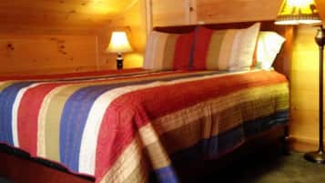 Quarto de cabana de madeira com uma cama, duas luminárias e uma janela.