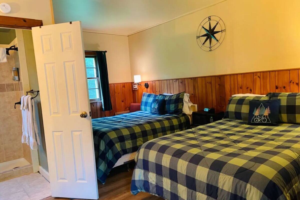 Quarto com duas camas, cabeceira de madeira, decoração de parede com bússola e uma porta.