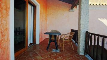 Varanda com piso de azulejos, uma mesa e duas cadeiras de vime.