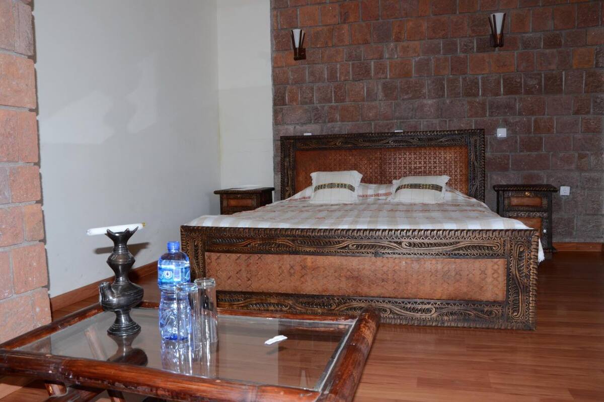Um quarto com uma cama grande, uma mesa de vidro e uma parede de tijolos.
