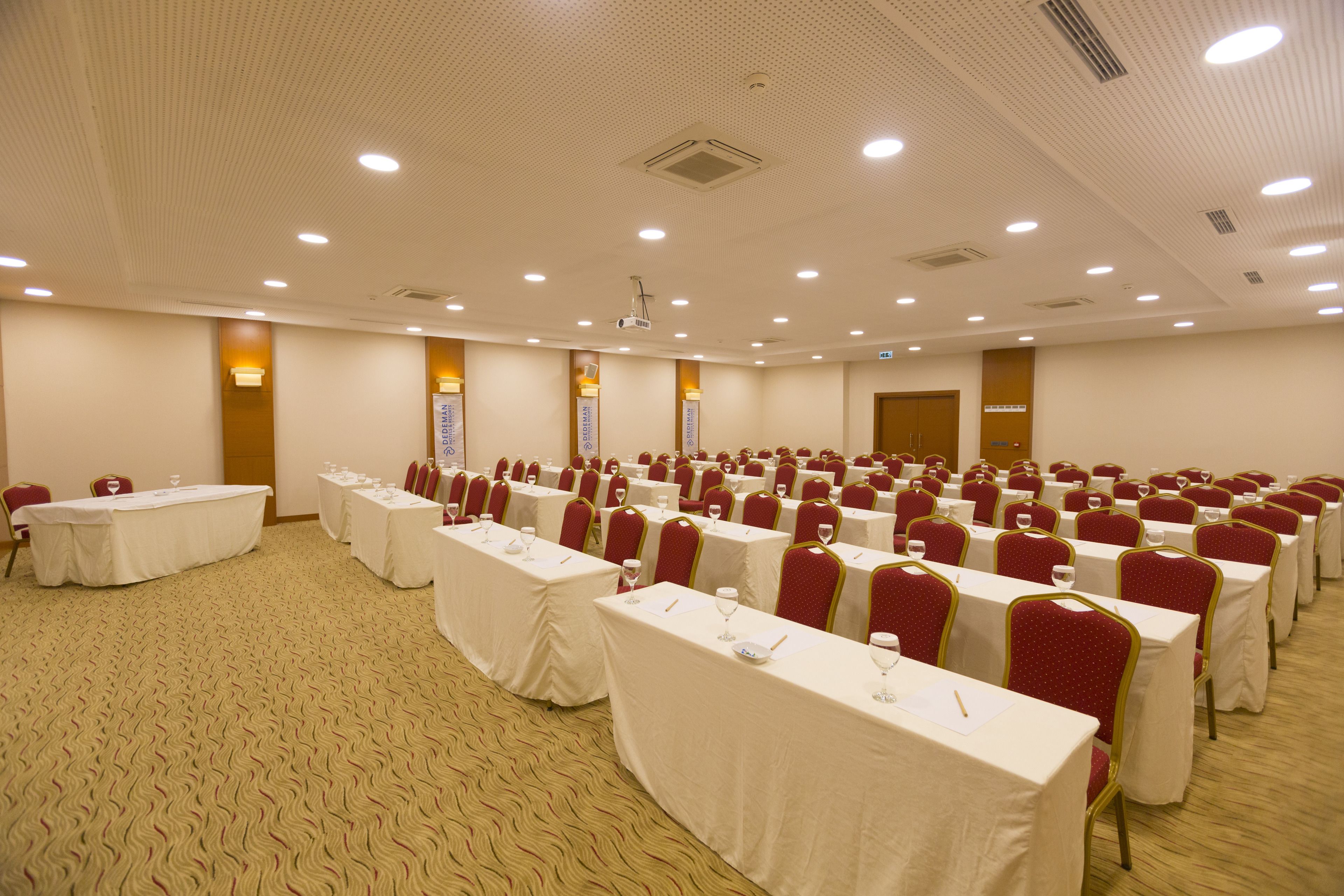Uma sala de conferências com fileiras de mesas e cadeiras, equipada com placas de identificação e copos d'água.