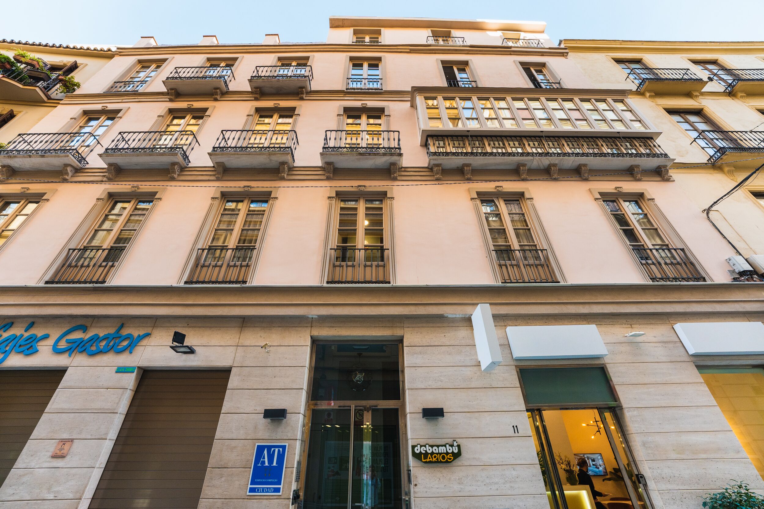 Edifício com várias varandas, fachada comercial com placa e entrada visível.