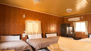 Quarto com duas camas, um sofá, uma mesa e um espelho.