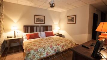Quarto de hotel com cama, duas mesas de cabeceira, escrivaninha e uma cadeira.