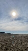 Uma praia com céu limpo e o sol brilhando.