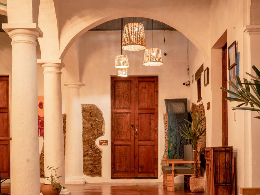 Um corredor amplo com teto alto, portas de madeira e luminárias pendentes de vime.