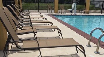 Uma área à beira da piscina com espreguiçadeiras e piscina.
