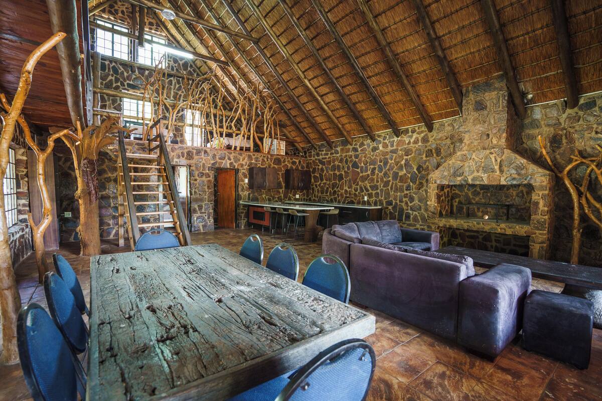 Um interior rústico com lareira de pedra, mesa de jantar de madeira e área de estar.