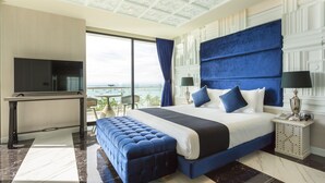 Quarto de hotel moderno com uma cama grande, TV de tela plana, escrivaninha e vista para o oceano.