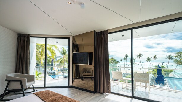 Quarto de hotel moderno com uma cama grande, TV de tela plana e varanda com vista para a piscina.