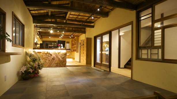 Um corredor amplo com teto de madeira, um balcão de recepção e uma escadaria para um segundo andar.