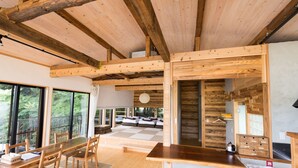 Interior em madeira com sala de jantar, cozinha e área de estar com vista para o exterior.