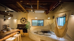 Um quarto acolhedor com balcão de madeira, assentos acolchoados, decoração com roda de navio e uma rede.