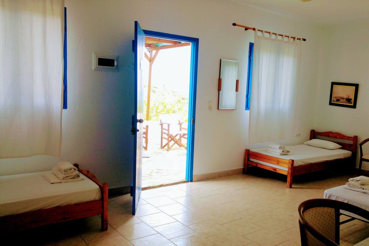 Quarto com duas camas, uma porta de madeira e vista para o exterior.