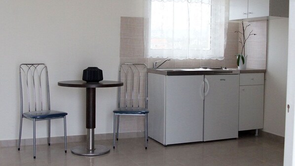 Uma cozinha compacta com pia, armários e duas cadeiras.