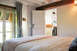 Quarto com uma cama, uma porta para um banheiro e uma luminária fixada na parede.