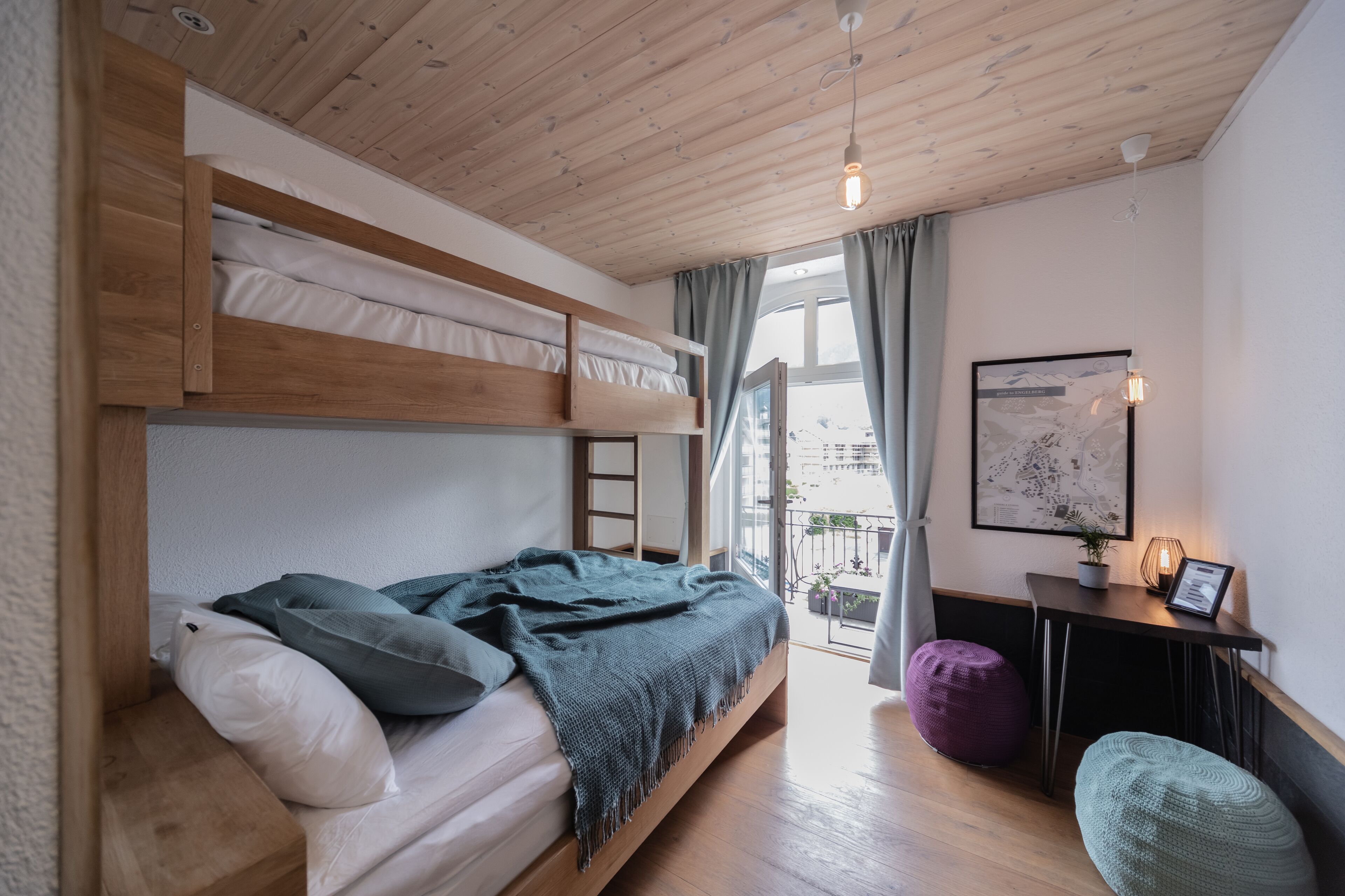 Quarto com beliche, escrivaninha e vista para a cidade.