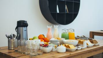 Uma mesa de café da manhã com diversos alimentos, bebidas e utensílios.