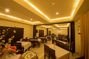 Um restaurante com várias mesas e cadeiras, iluminação acolhedora e uma placa visível com a inscrição 'Infinity'.