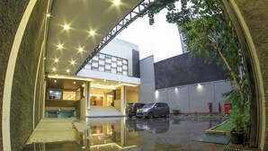 Um edifício moderno com piso refletente molhado, uma escada que leva à entrada e um carro estacionado.