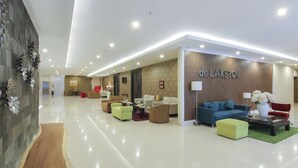 Um hall moderno de hotel com balcão de recepção, área de estar e um letreiro 'de LAXSTON'.