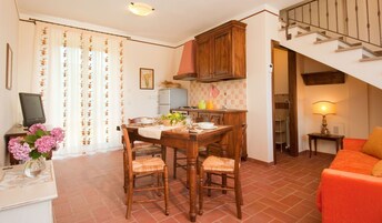 Uma sala de estar acolhedora com uma mesa de jantar, cadeiras de madeira, um sofá e uma escada.