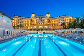 Um hotel grande com piscina, várias varandas e uma entrada imponente.