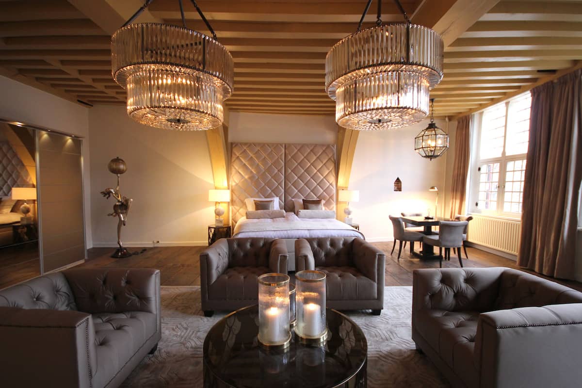 Um quarto espaçoso com uma cama grande, dois sofás, uma mesa de centro com velas e um candelabro.