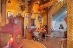 Um interior acolhedor com um banco xadrez, cadeiras de vime, um forno de pedra e uma escada com corrimão de madeira.