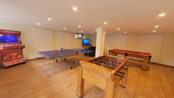 Um quarto com mesa de pingue-pongue, mesa de futebol de mesa e um fliperama Neo-GEO.