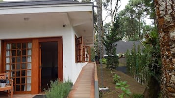 Uma casa com deck de madeira, varanda coberta e jardim com diversas plantas.