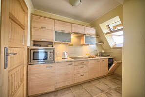 Apartamento, 2 quartos | Cozinha americana privada | Geladeira, micro-ondas, fogão, cooktop