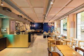Um restaurante com área de bar, mesas e janelas amplas.