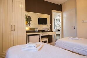 Quarto de hotel com duas camas, uma escrivaninha, televisão de tela plana, espelho e armário.