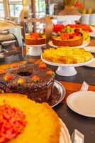 Um buffet com diversos doces, incluindo um bolo de chocolate, um bolo amarelo e uma salada de frutas.