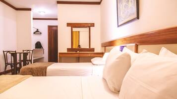 Quarto de hotel com duas camas, cabeceira de madeira, espelho, escrivaninha com cadeira e cabideiro.