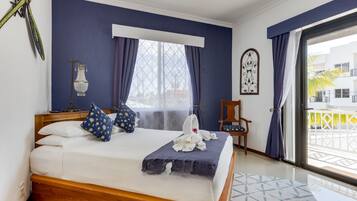 Quarto de hotel com cama, janela, poltrona e vista para a varanda.