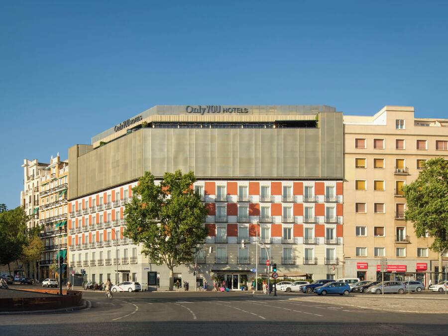Um hotel com fachada moderna, vários andares e uma sinalização chamativa.
